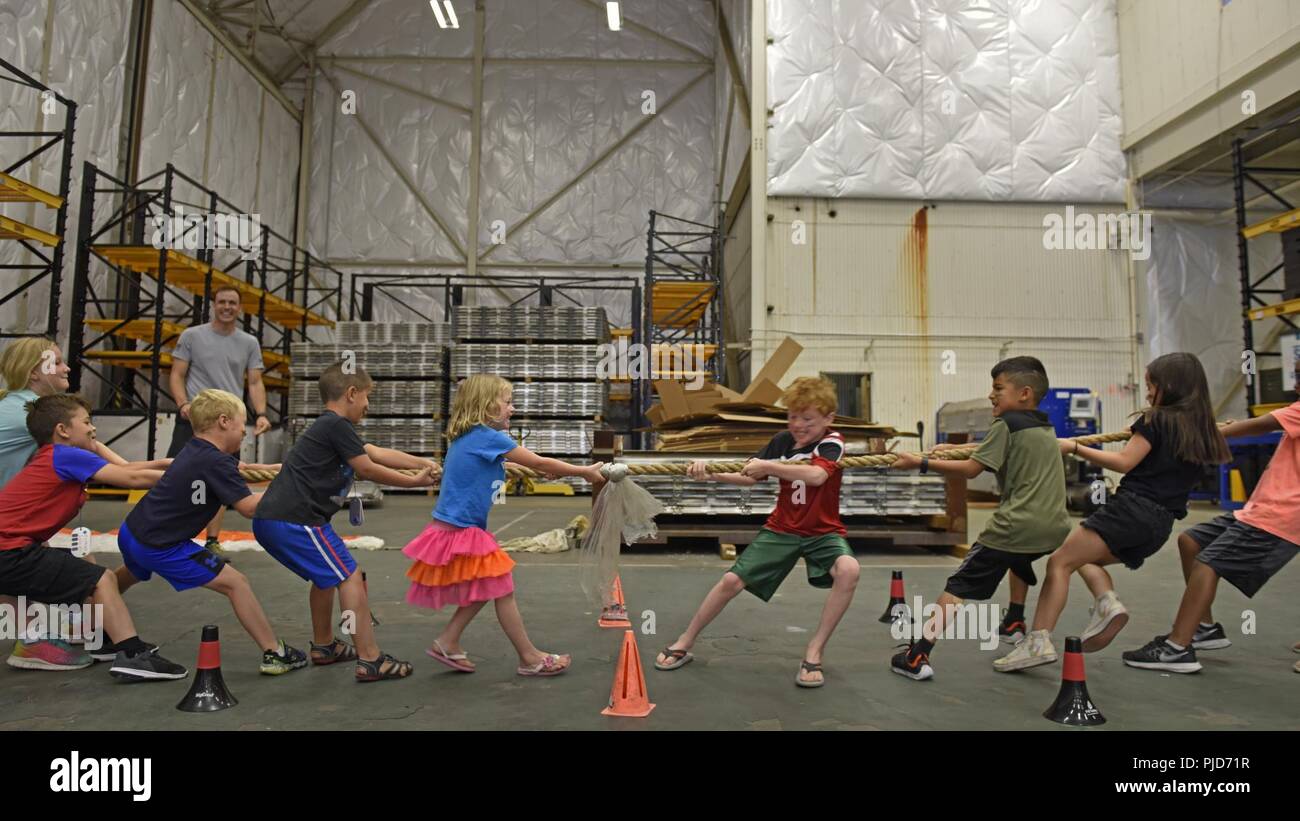 A group of military children compete in a game of tug-of-war during ...