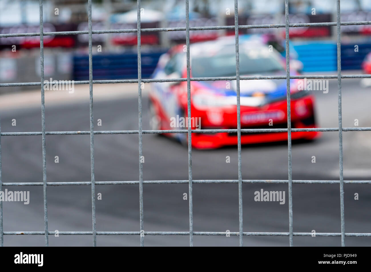 Motorsport car racing on asphalt road. View from the fence mesh netting ...