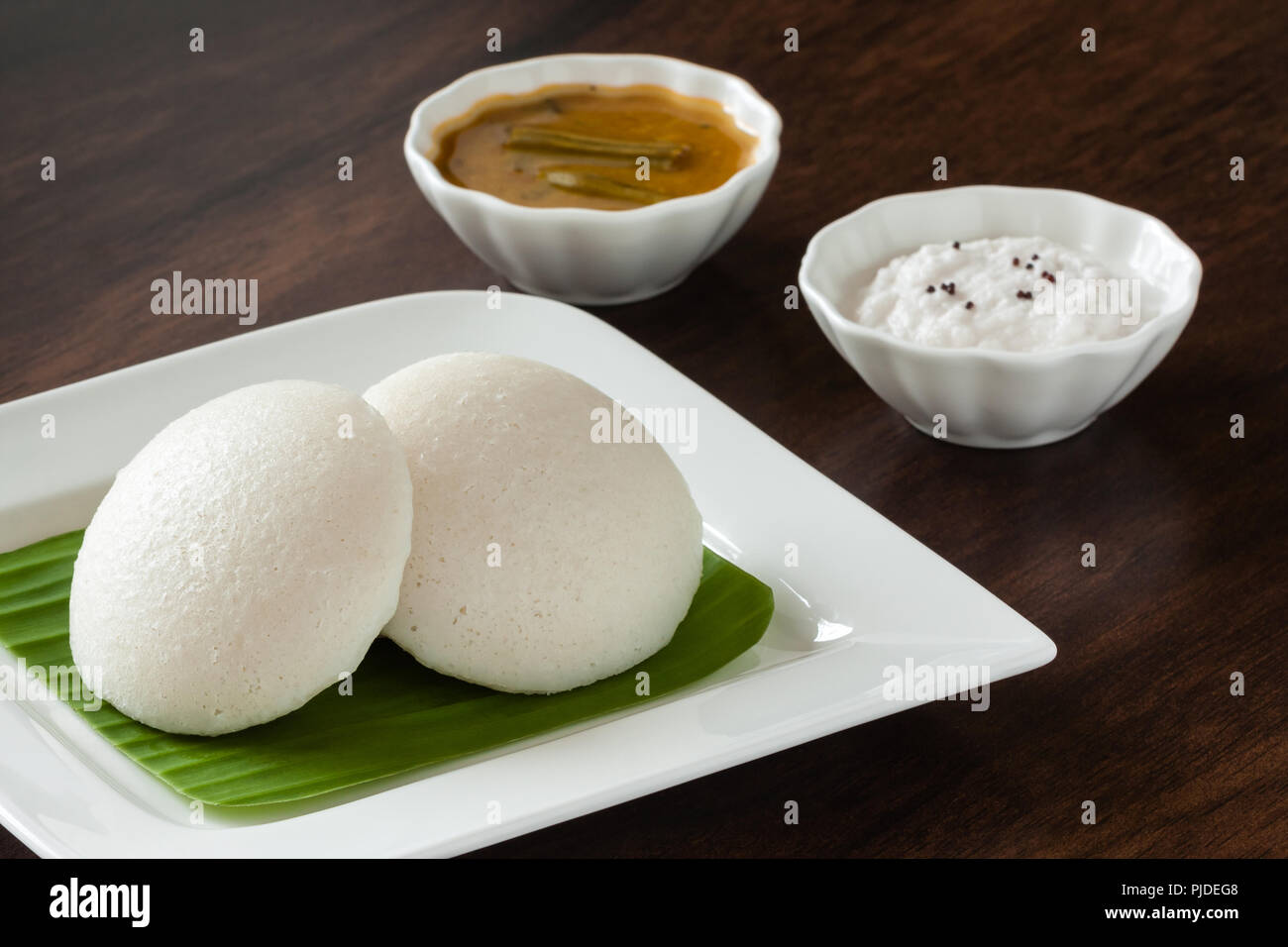 Fresh steamed Indian Idly (Idli / rice cake) arranged on banana leaf ...