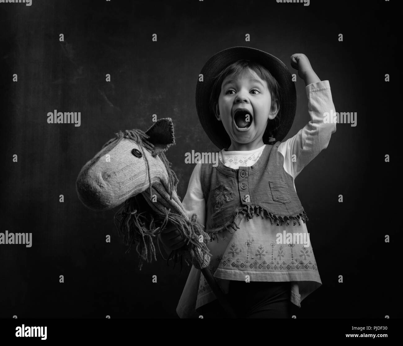 Cute little girl dressed like a cowboy playing with a homemade horse ...