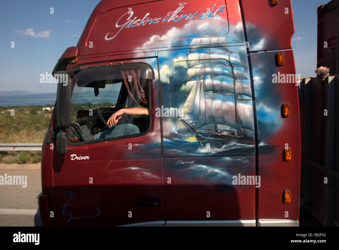 Truck driver driving a truck decorated with an image of a sailing ship ...