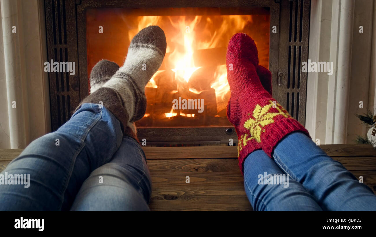 Closeup image of romantic couple and jeans and woolen socks warming by ...