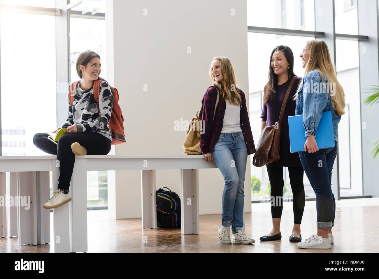 Female university students chatting together in university lobby Stock ...