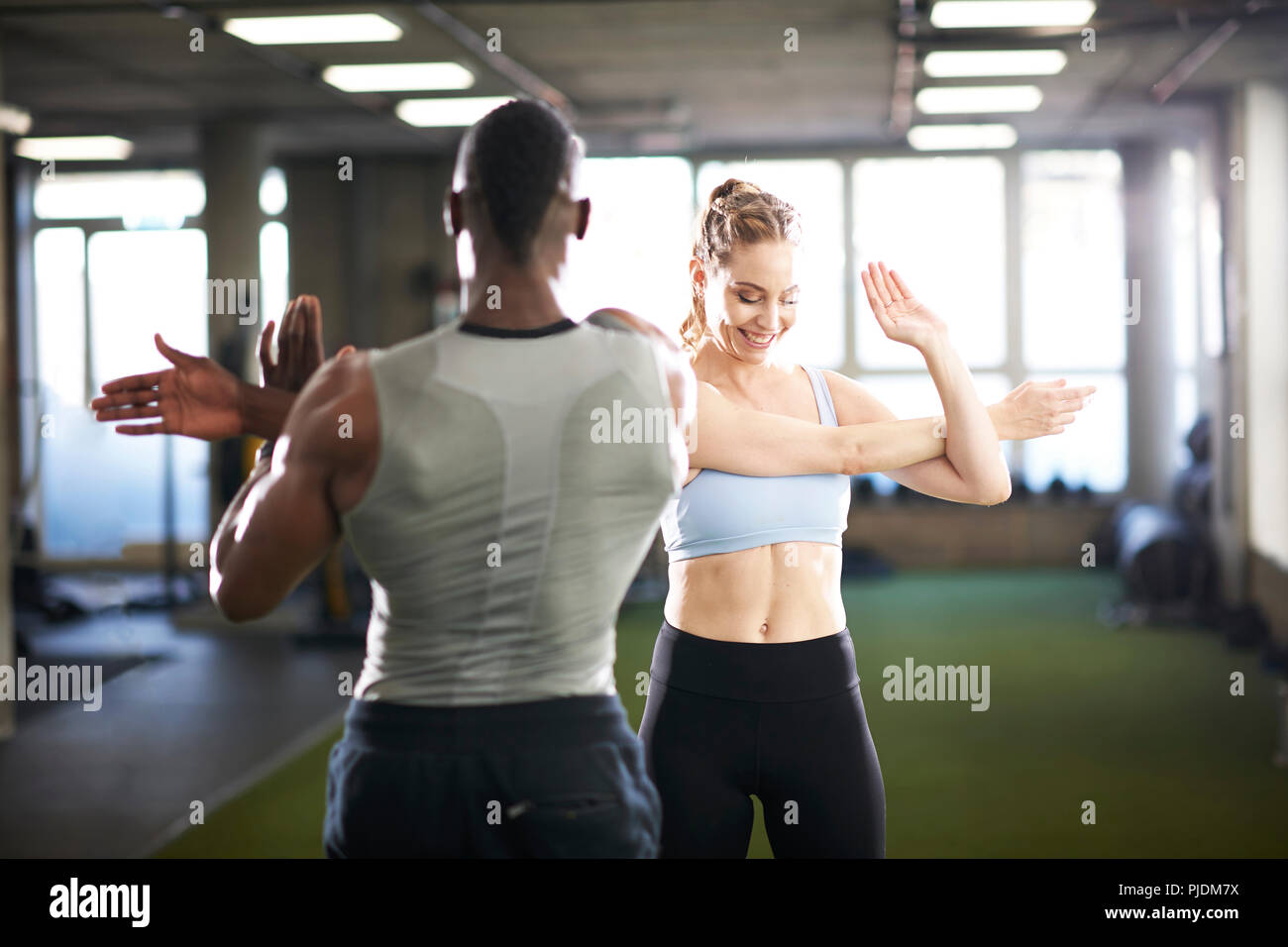 Trainer and female client doing stretching exercise in gym Stock Photo ...