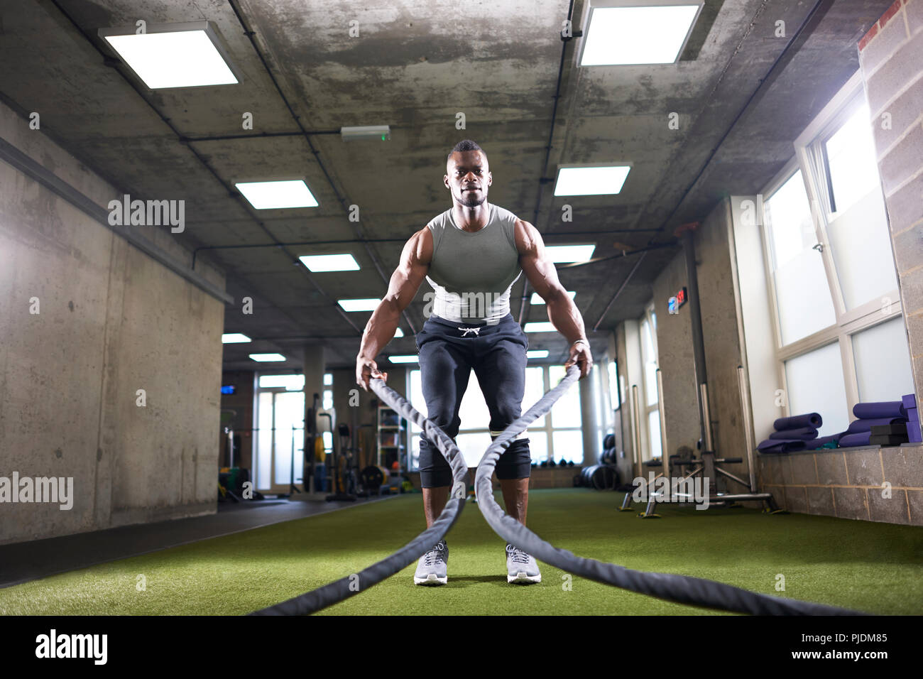 Man using battle ropes in gym Stock Photo - Alamy
