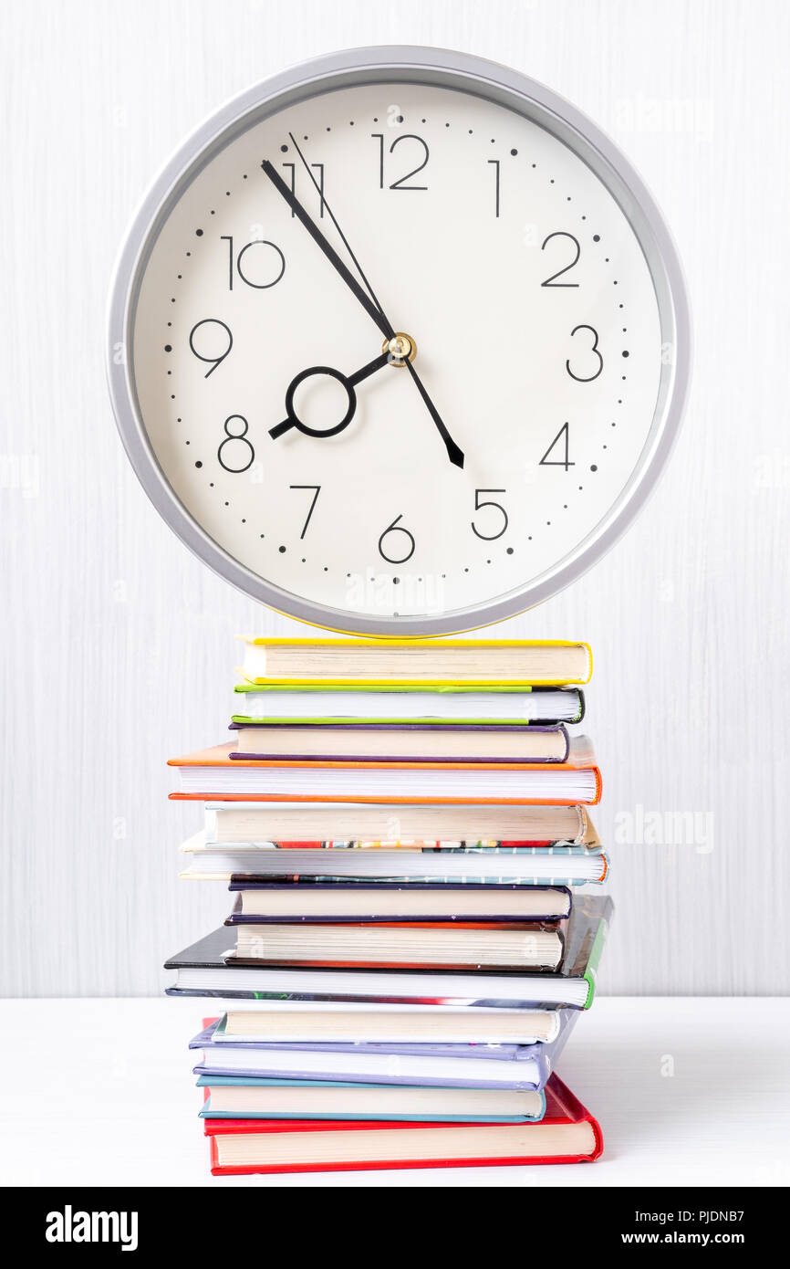 Wall clock on top of a stack of books Stock Photo - Alamy