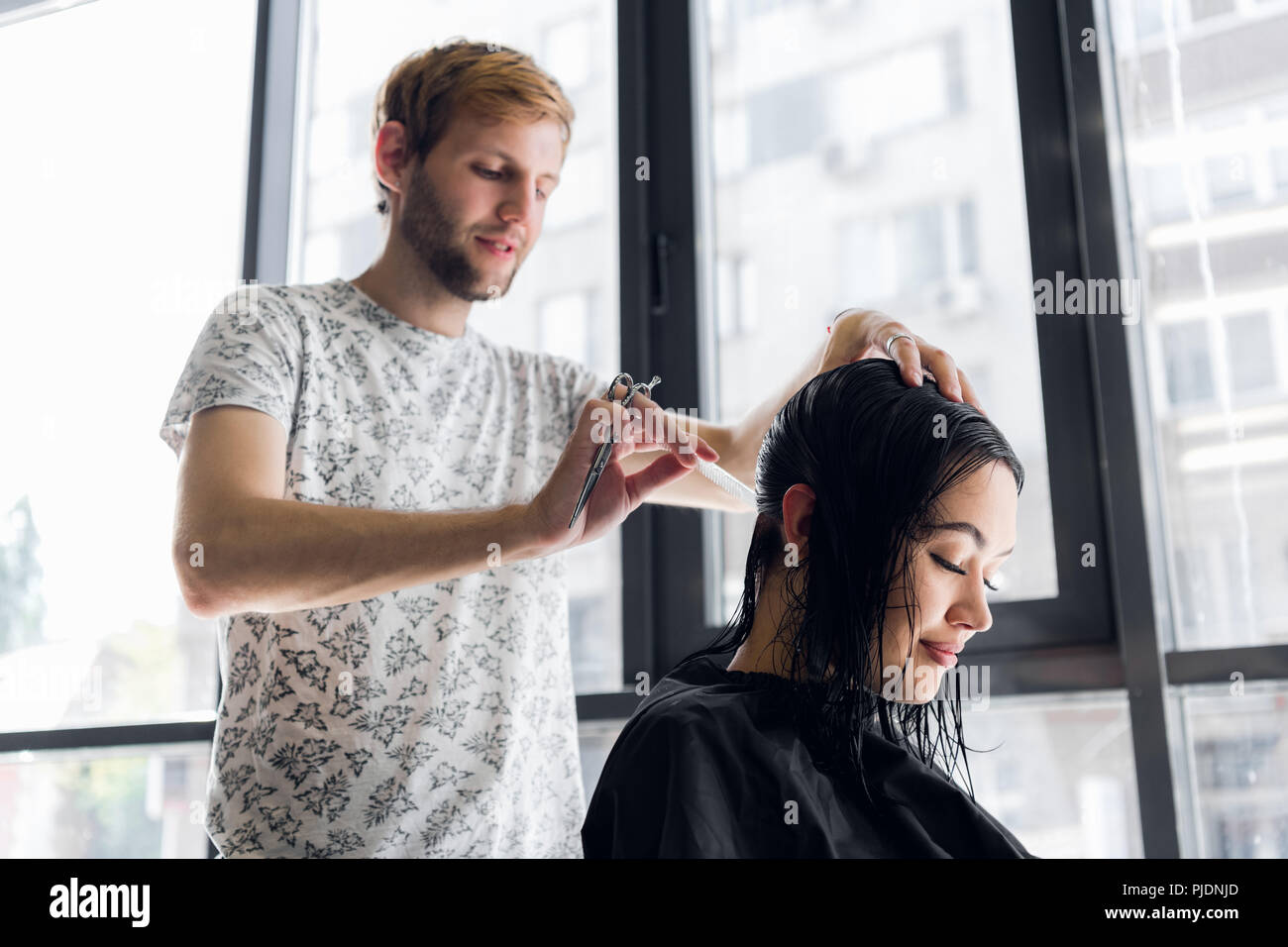 Hairdresser cutting client's hair in salon with scissors closeup. Using ...