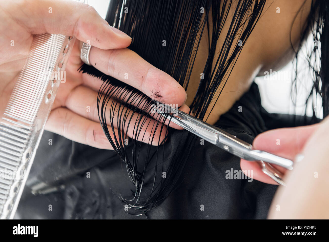 Hairdresser cutting client's hair in salon with scissors closeup. Using ...