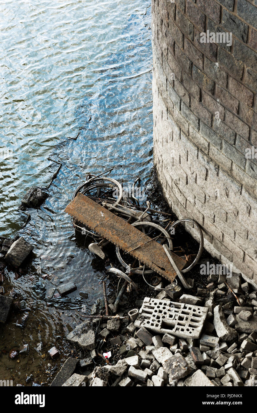 Trash and debris underneath bridge including a bike and other various ...