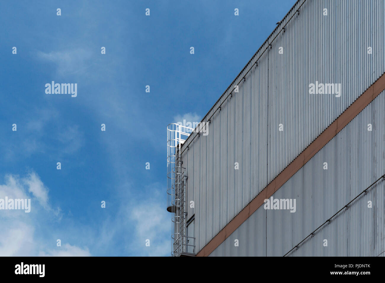 Ladder running along side factory wall with azure blue sky behind Stock ...