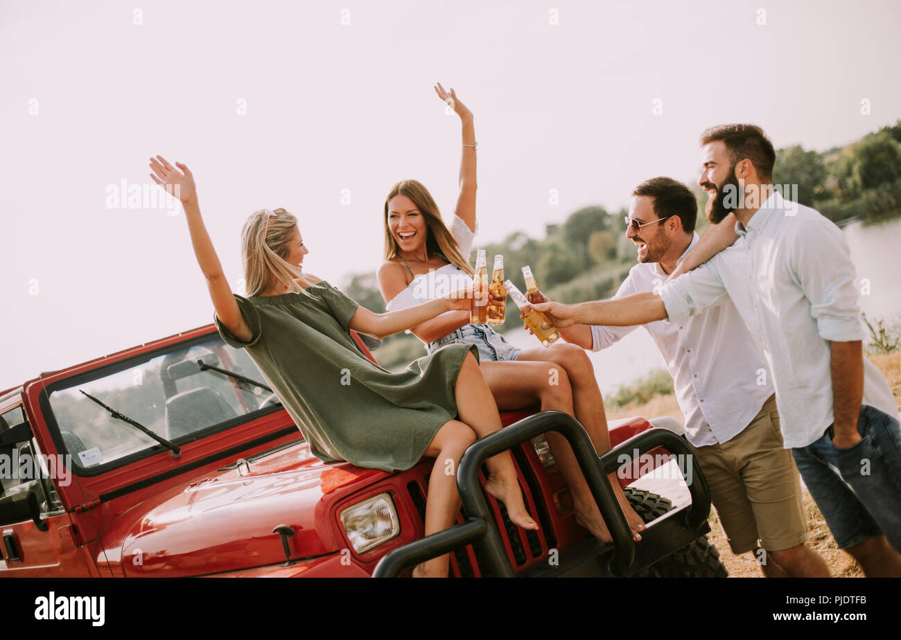 Young people drinking and having fun by car outdoor at hot summer day ...