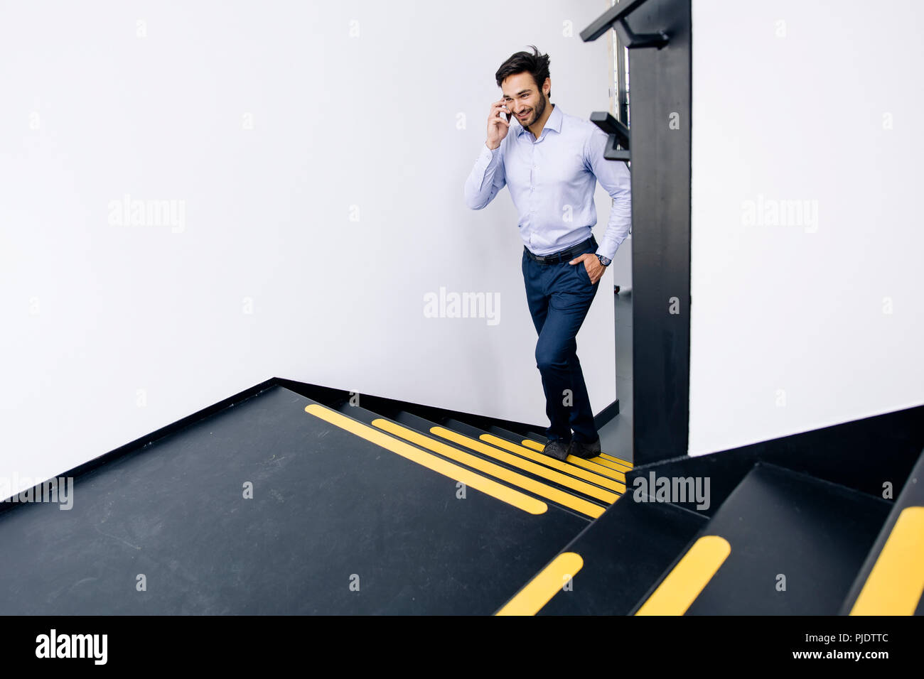 Young businessman talking on mobile phone and climbing on the stairs in ...