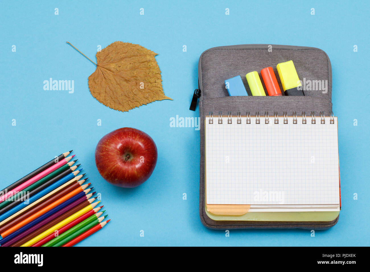 Color pencils, apple, dry leaf, open exercise book on bag-pencil case ...