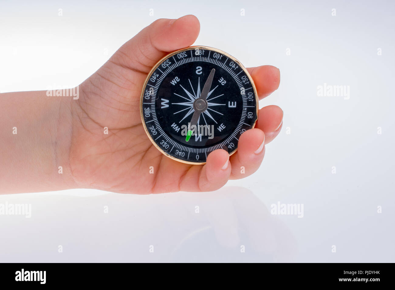 Child hand holding a compass on a white background Stock Photo - Alamy