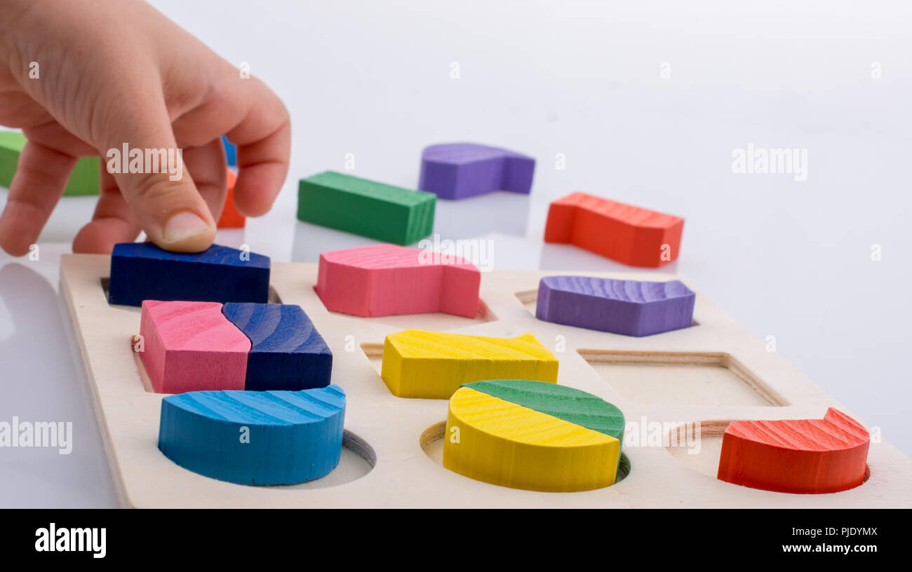Colorful wooden pieces of a logic puzzle in hand Stock Photo - Alamy