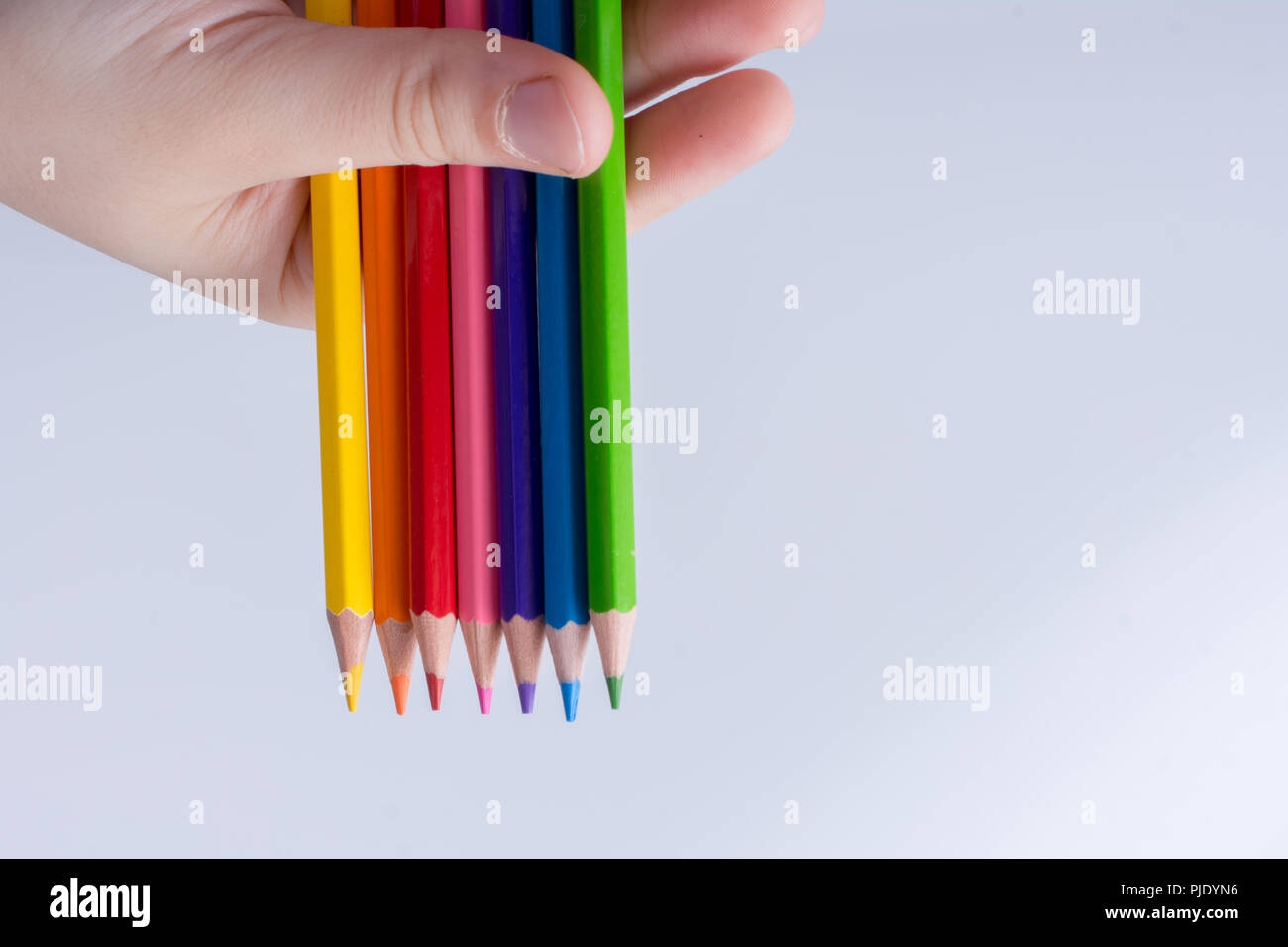 Hand holding color Pencils placed on a white background Stock Photo - Alamy