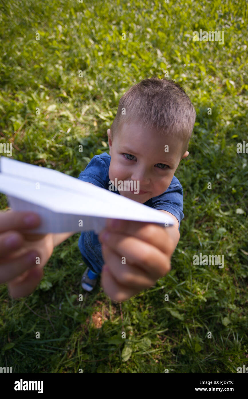 Cute caucasian child playing paper airplane in the park outdoors in ...