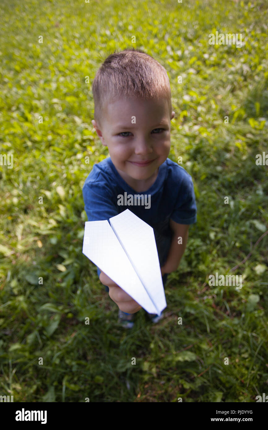 Cute caucasian child playing paper airplane in the park outdoors in ...
