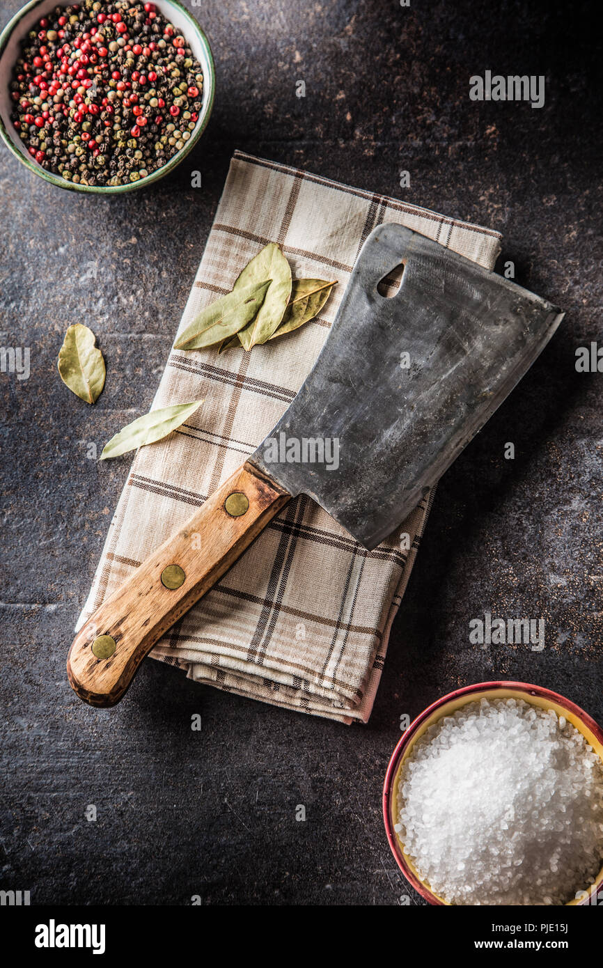 Old meat butcher on dark concrete board with spices salt and pepper ...