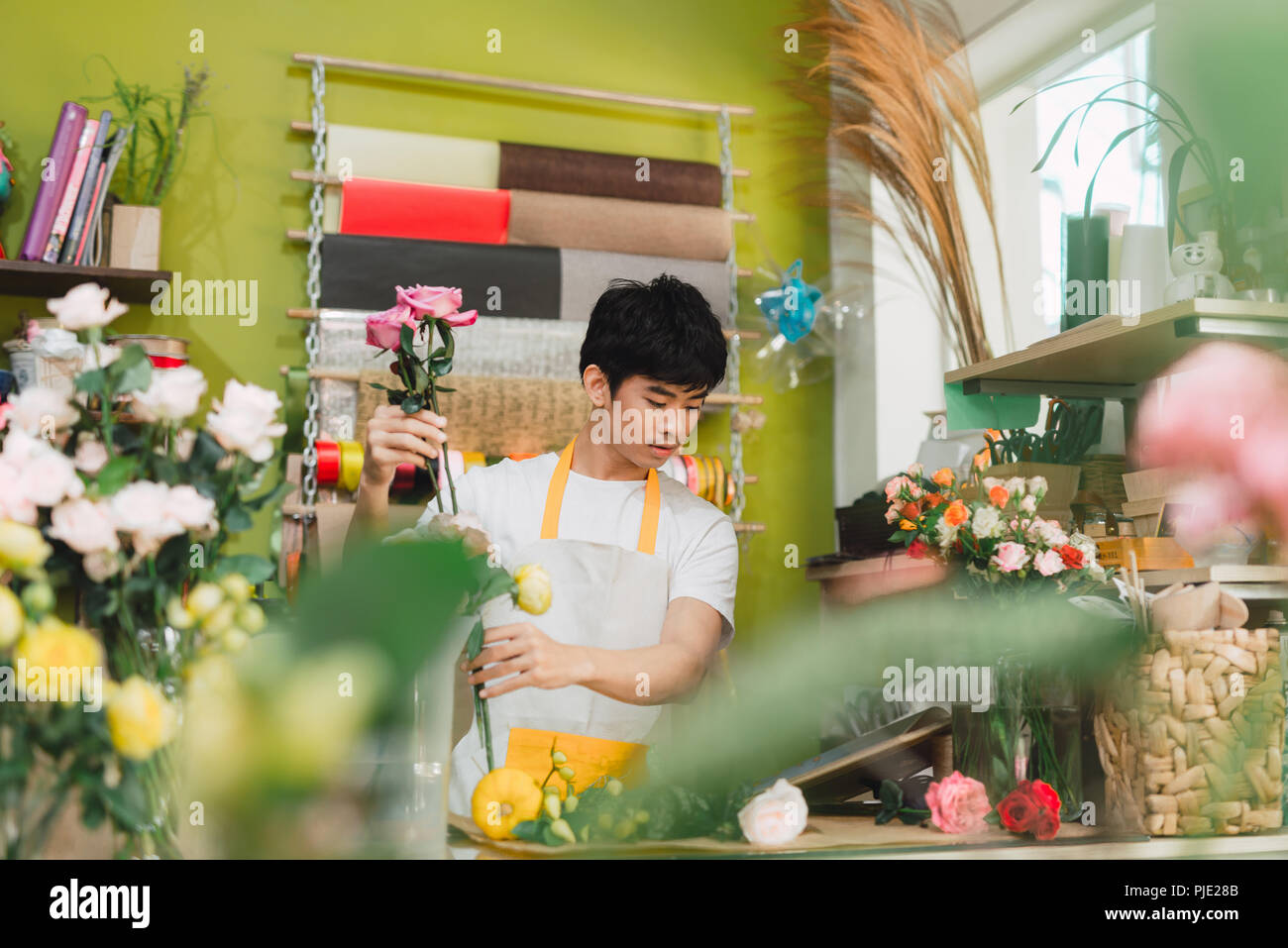 Small business. Male florist making rose bouquet at counter desk in ...