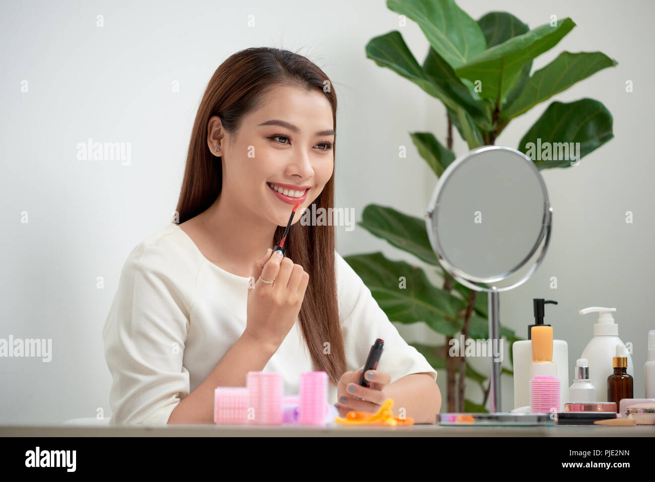 Young beautiful woman making make-up near mirror,sitting at the desk ...