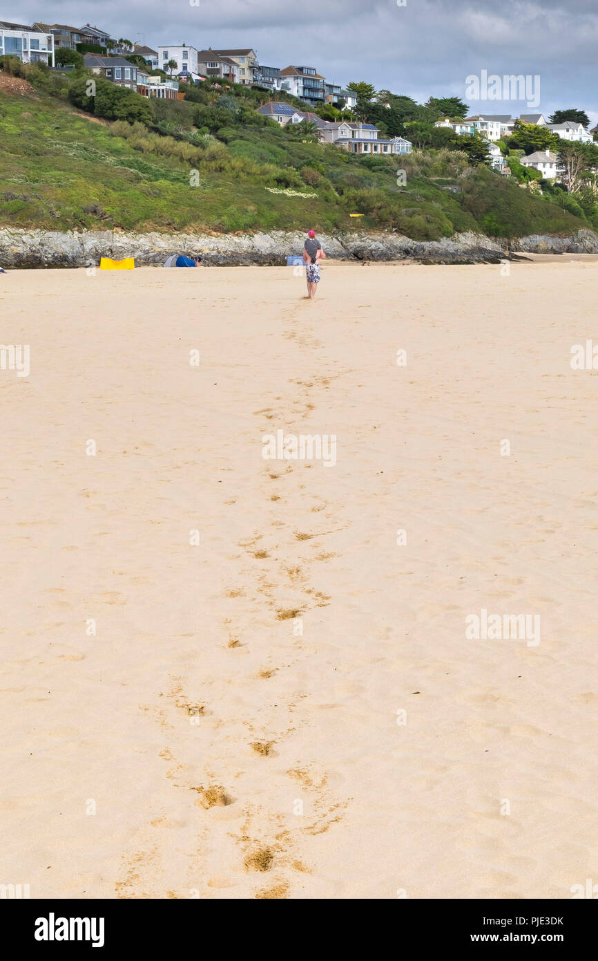 The footsteps in the sand of a holidaymaker carrying his young child on ...