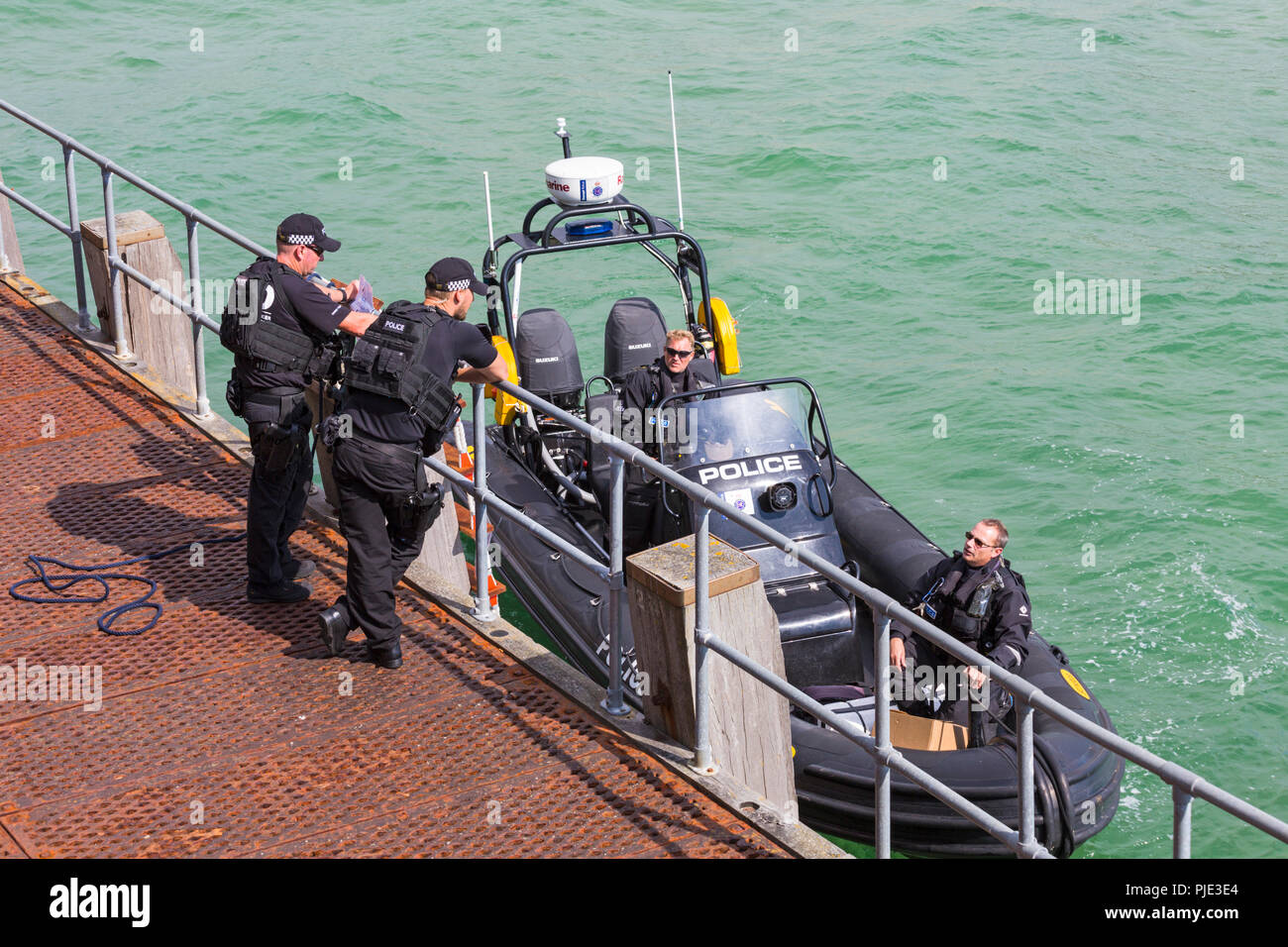 police in patrol boat talking to armed police on the pier during ...