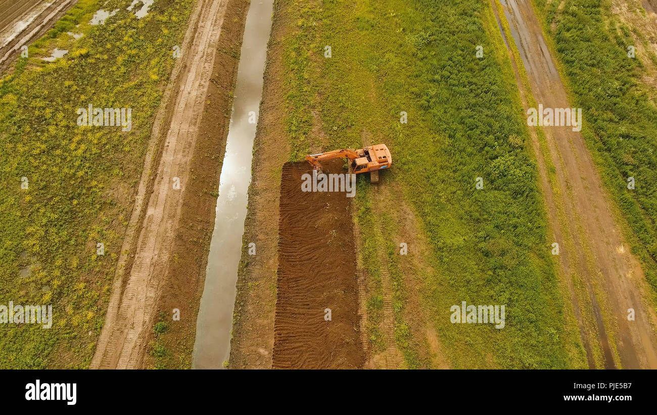 Excavator is digging an irrigation canal. Aerial view:Excavator digging ...