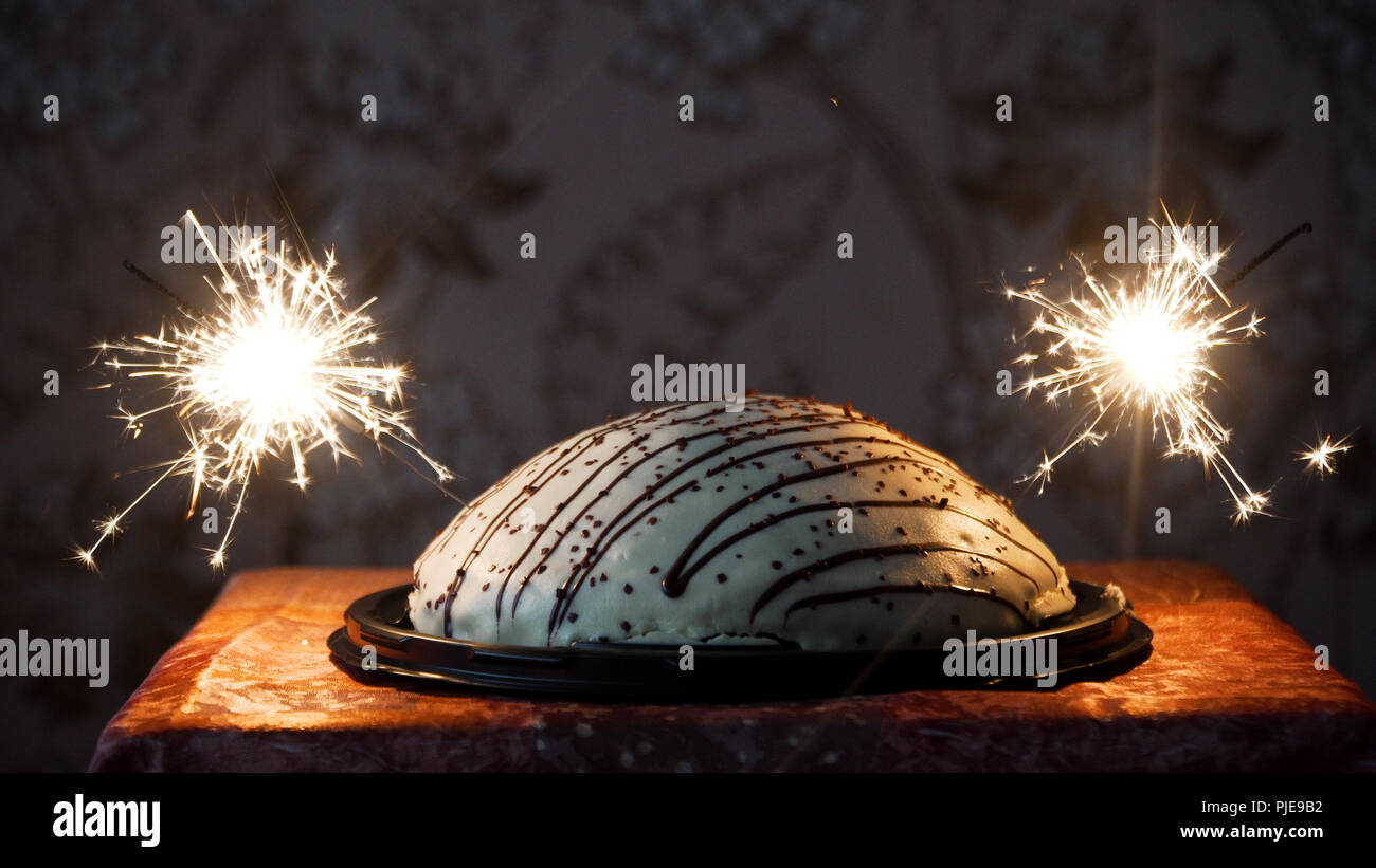 Celebratory cake with sparkles and Bengal light in dark room Stock ...