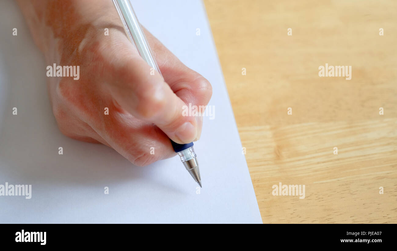 Front view, woman's hand, writing on a piece of paper sitting in the ...