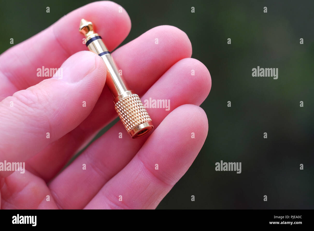 Adapter for audio. The adapter between the fingers Stock Photo - Alamy