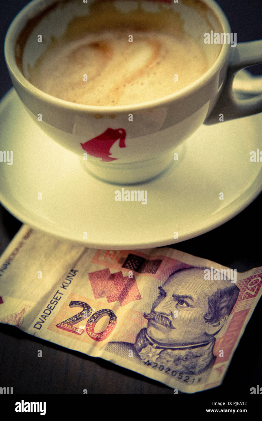 A lone coffee cup and saucer with a 20 kuna banknote on the table in ...