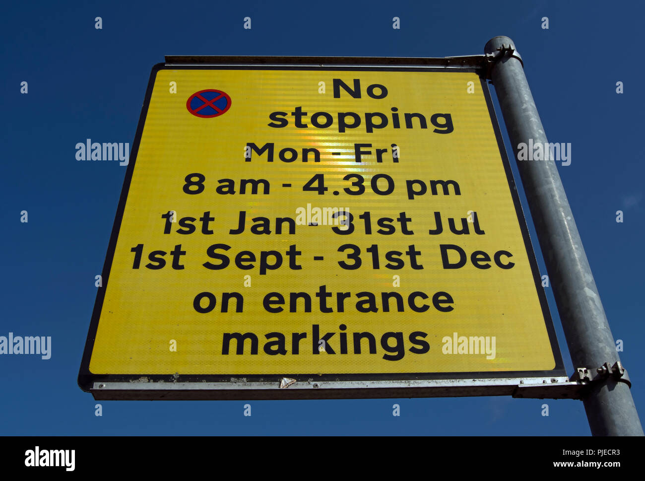 yellow and black road sign indicating no stopping on entance markings ...