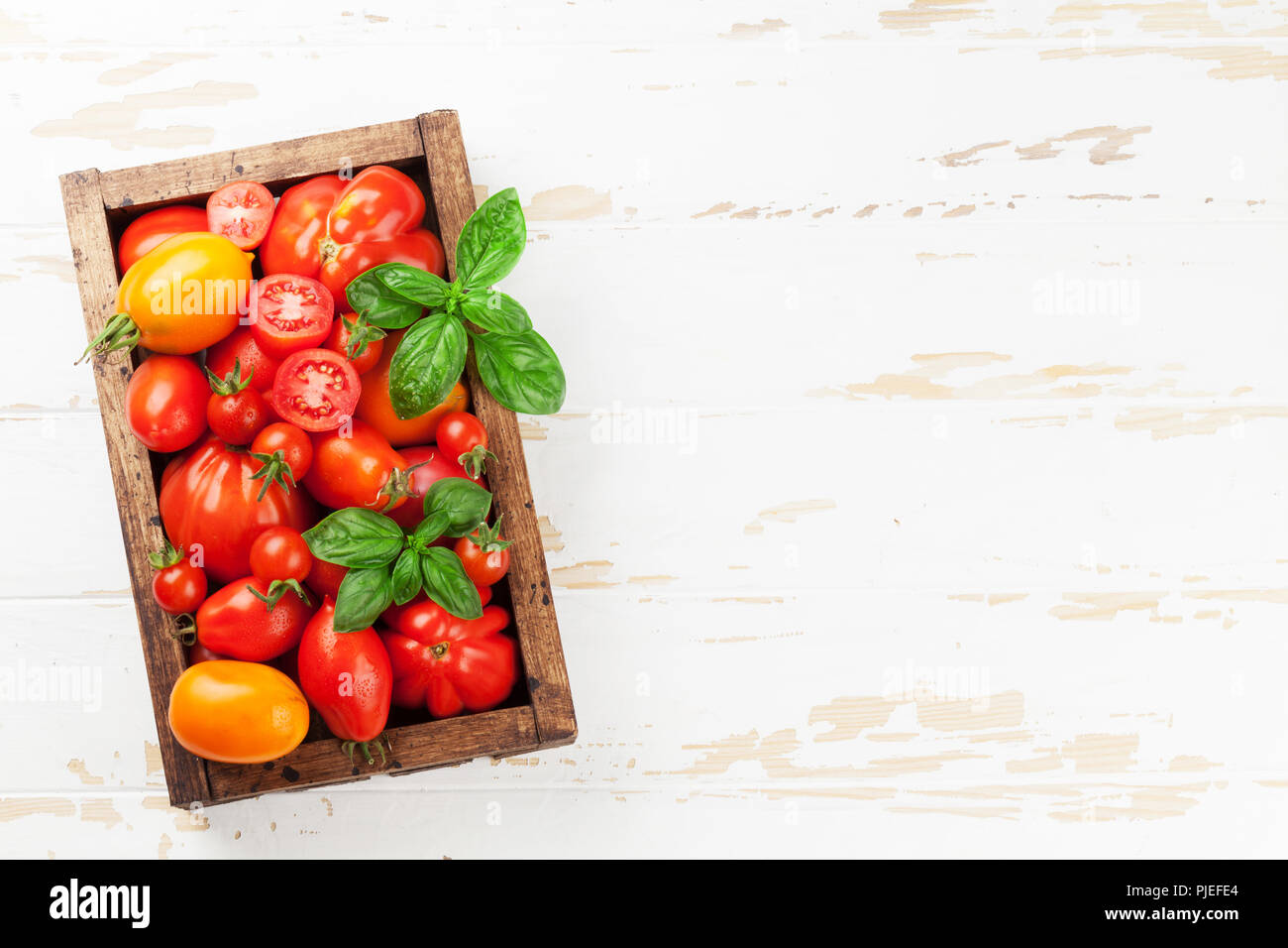 Fresh garden tomatoes and basil on cooking table. Top view with space ...