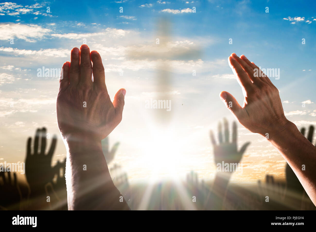 Human Hand Raising Hands With Cross In The Center Against Cloudy Sky ...