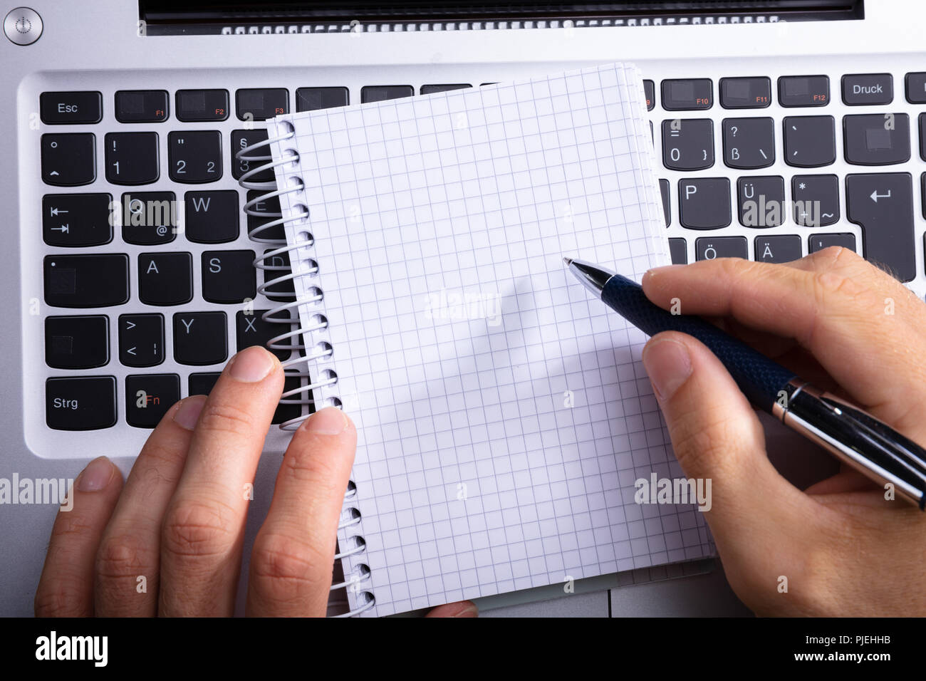 Person's Hand Writing On Spiral Notepad Over Laptop Keyboard Stock ...
