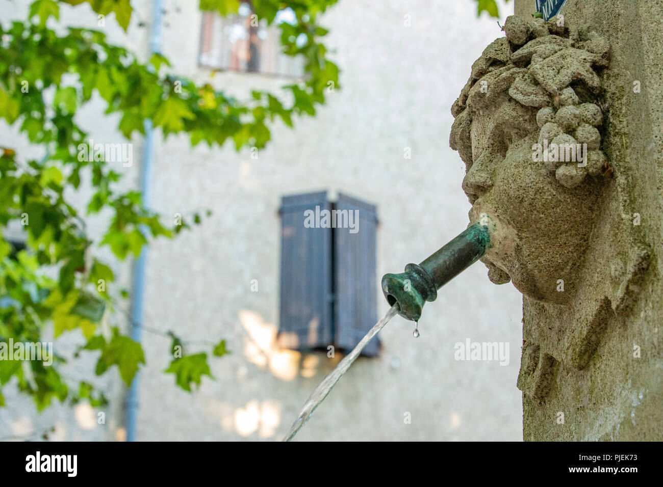 Old fountain with water and flowers and window of Manosque home in ...
