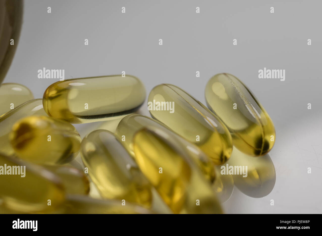 Clear gel capsules close up reflecting on a white table Stock Photo - Alamy