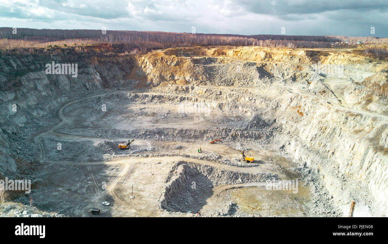 Aerial view of opencast mining quarry with of machinery at work, white ...