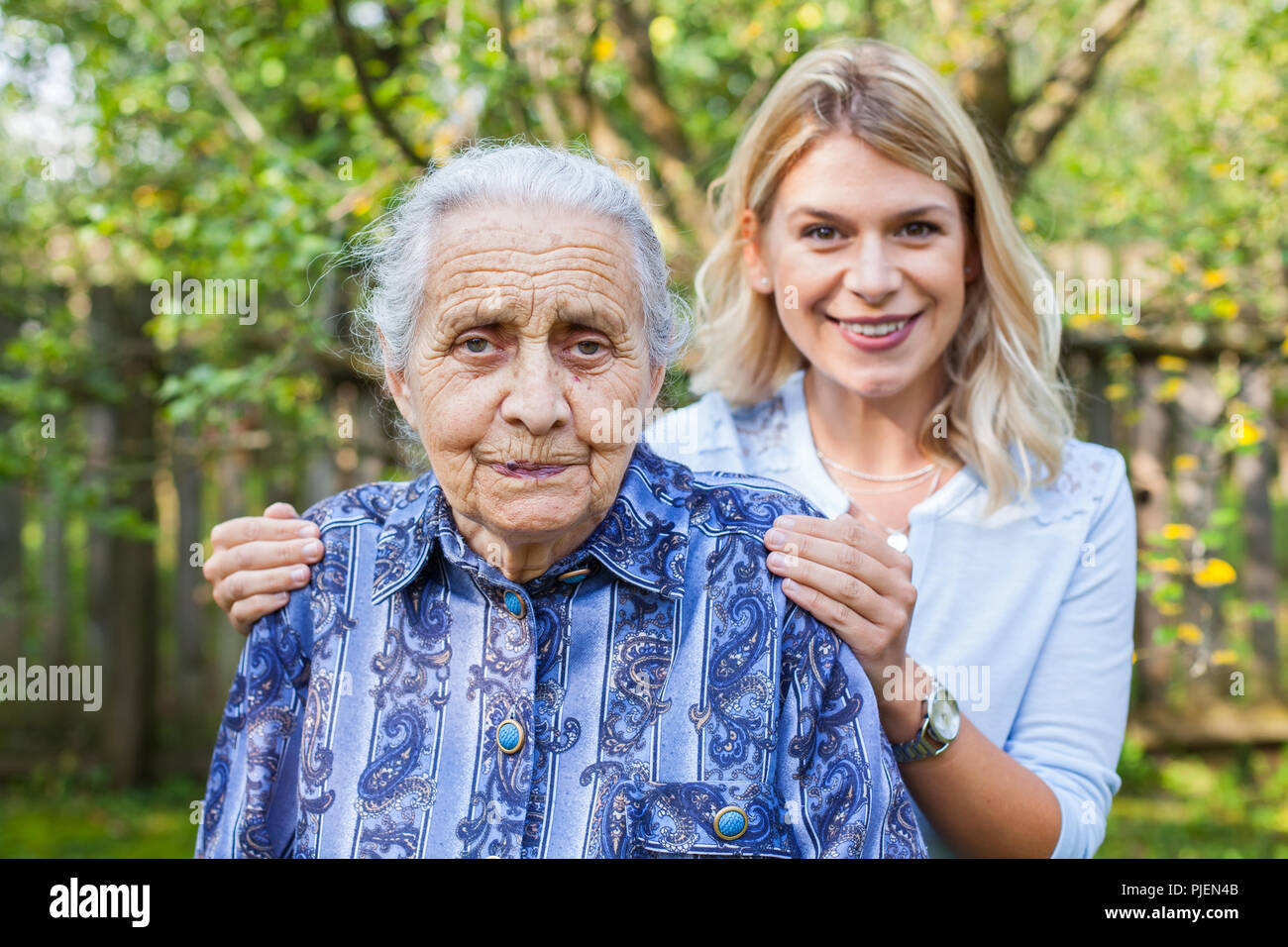 Smiling young caretaker walking with senior lady in the garden Stock ...