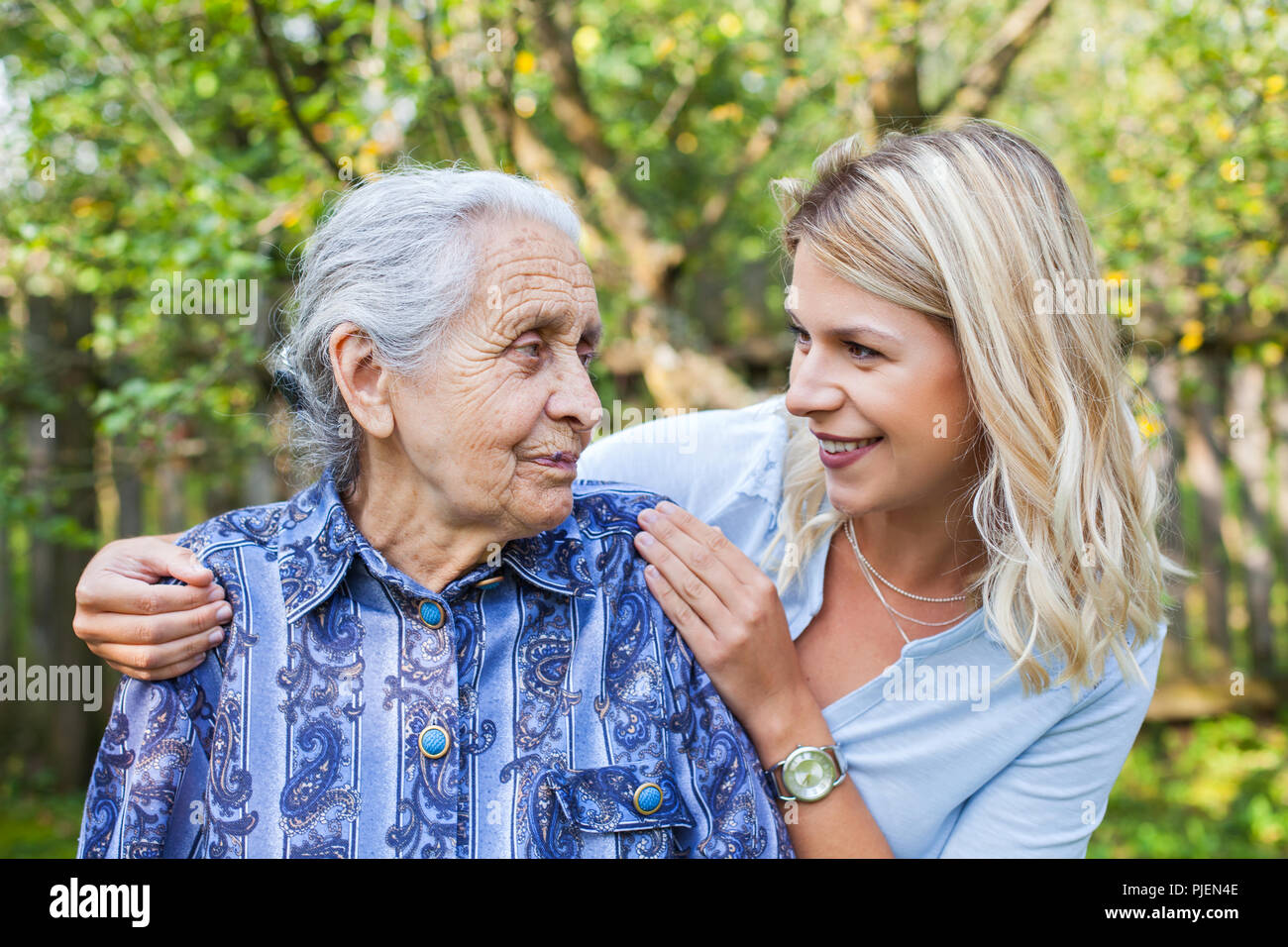 Smiling young caretaker walking with senior lady in the garden Stock ...