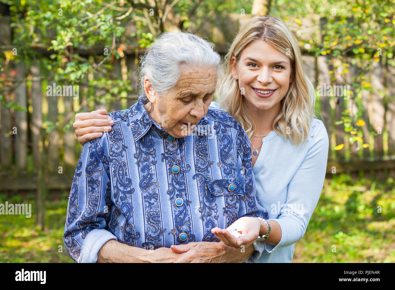 Disabled old lady taking medical pills from friendly carer's hand ...