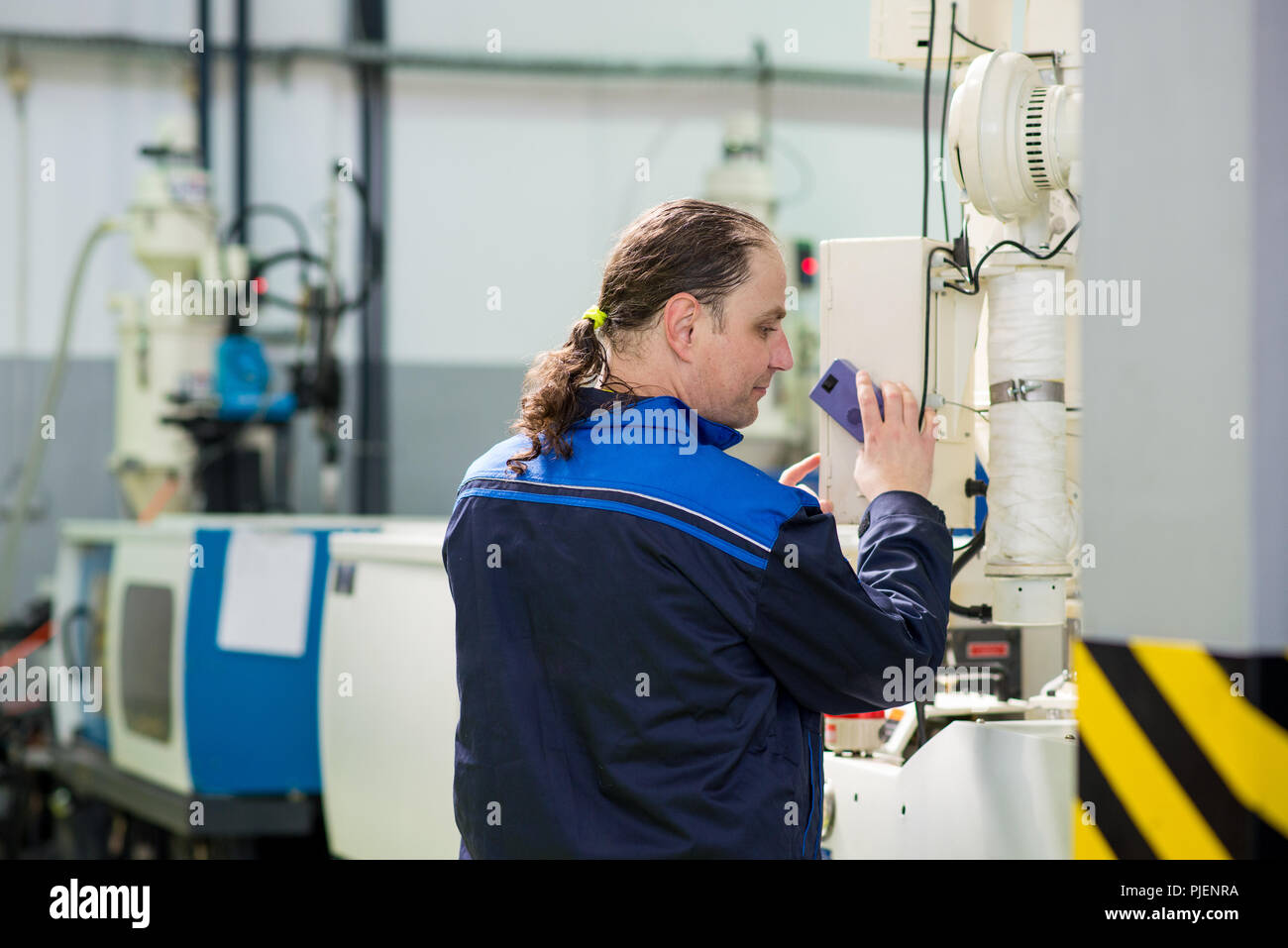 Factory worker working on a factory machine Stock Photo - Alamy