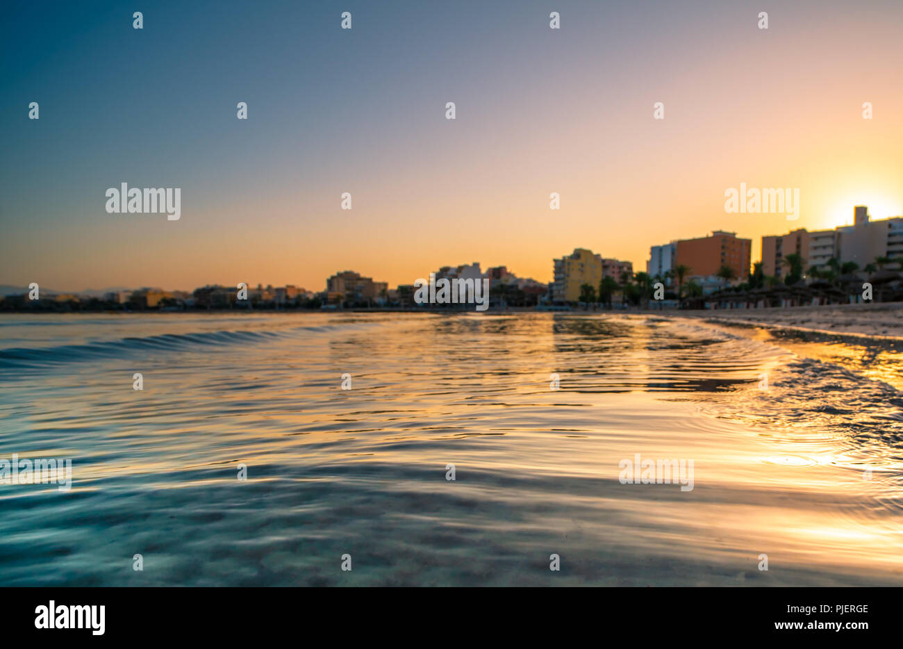 Wavy curves of sea is covered in golden sunset light. Sea at sunset ...