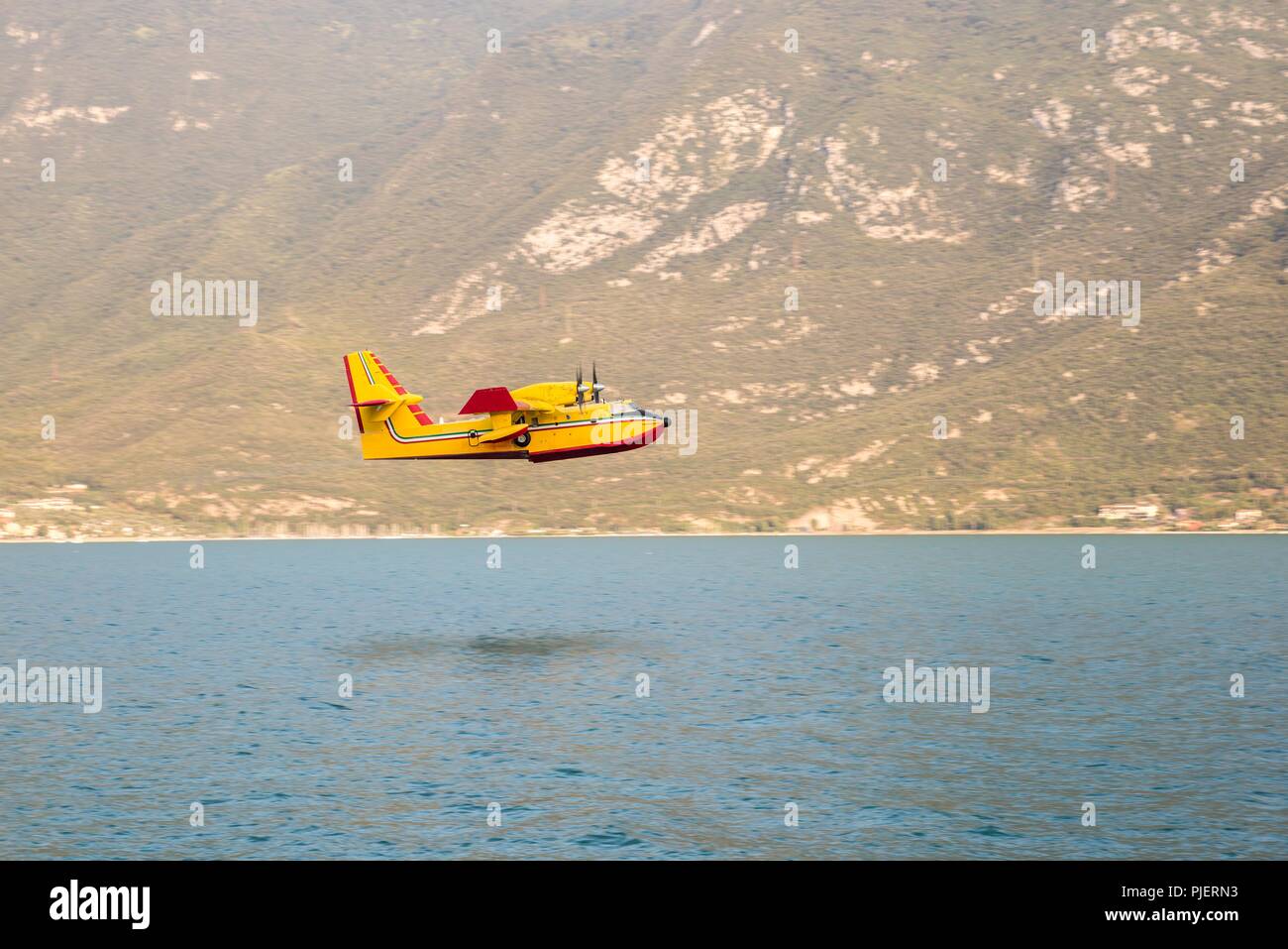 Water bomber firefighting plane over Garda Lake during forest fire in ...
