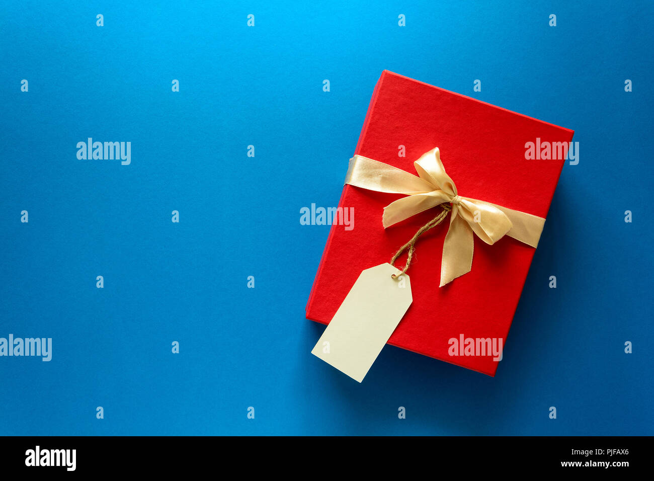 Top view on red Christmas gift box decorated with ribbon on blue paper ...