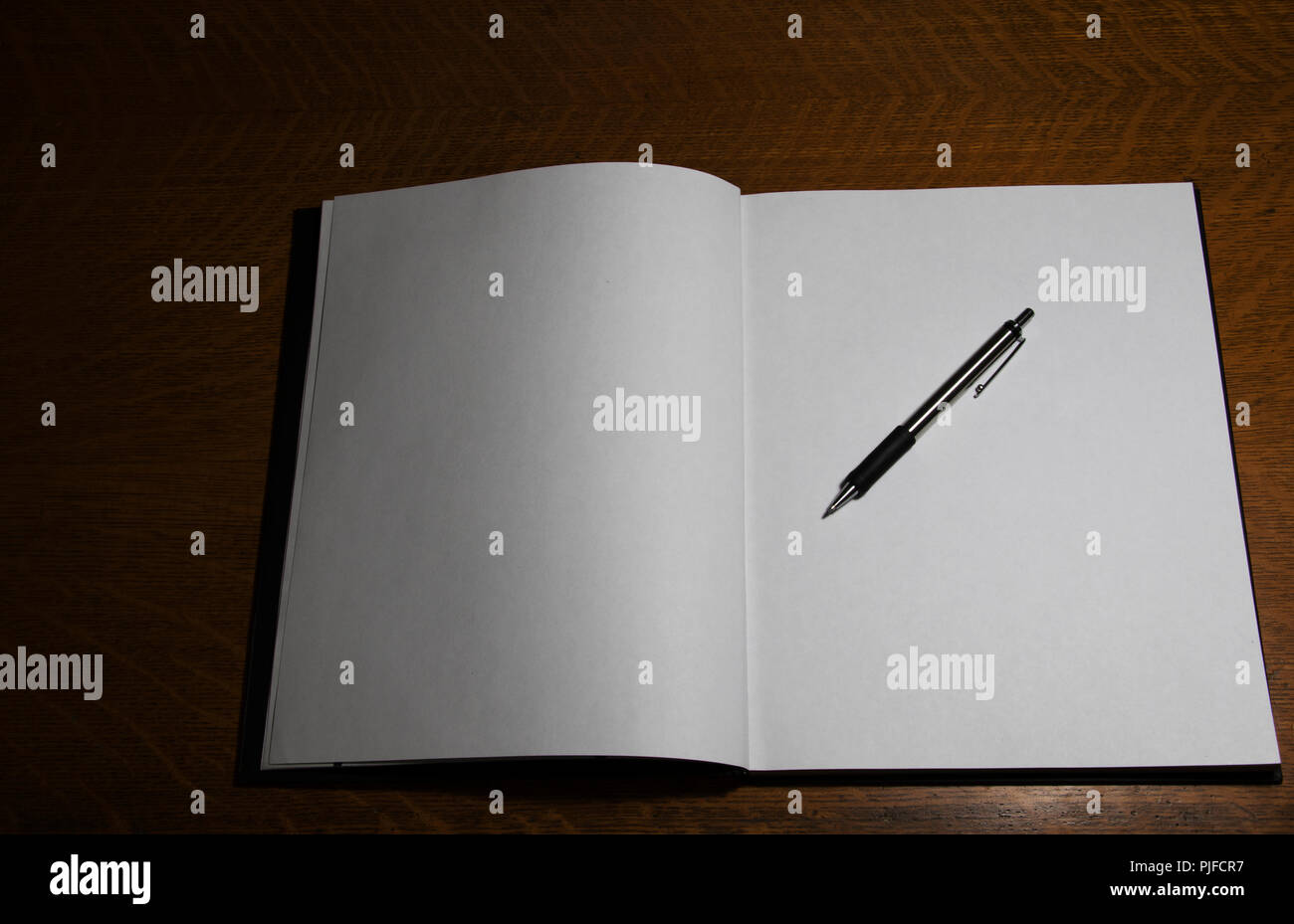 Open notebook with blank white pages on a desk with a pen. Writing a ...