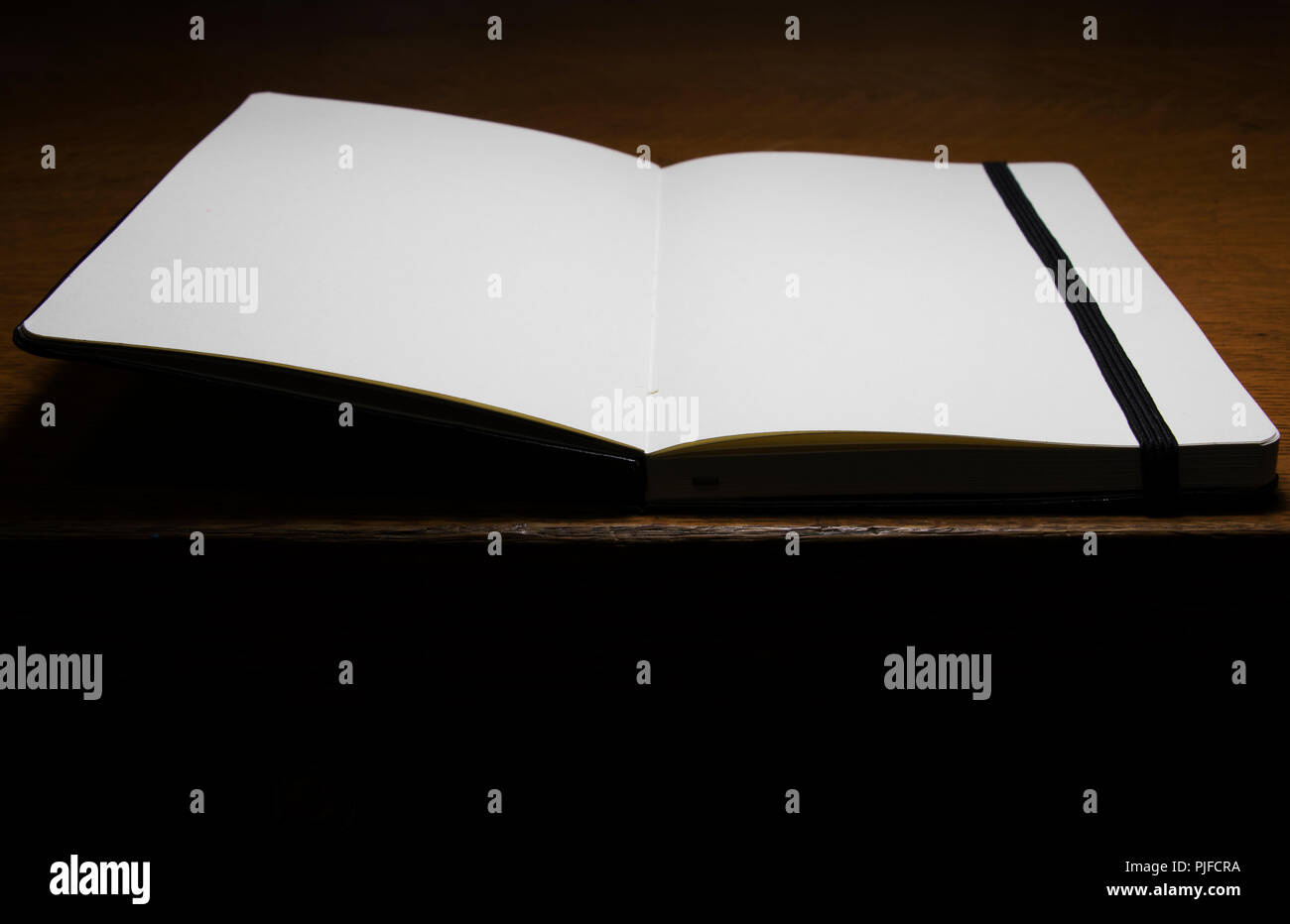 Open book with blank pages on an office desk. White paper of a ...