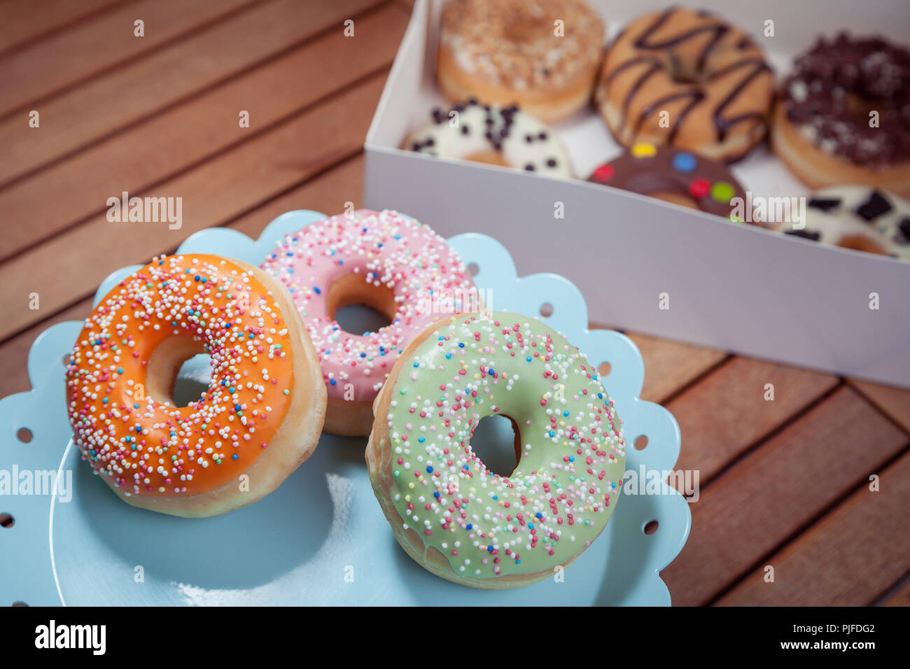 donuts on a turquoise plate on wood table with straws Stock Photo - Alamy