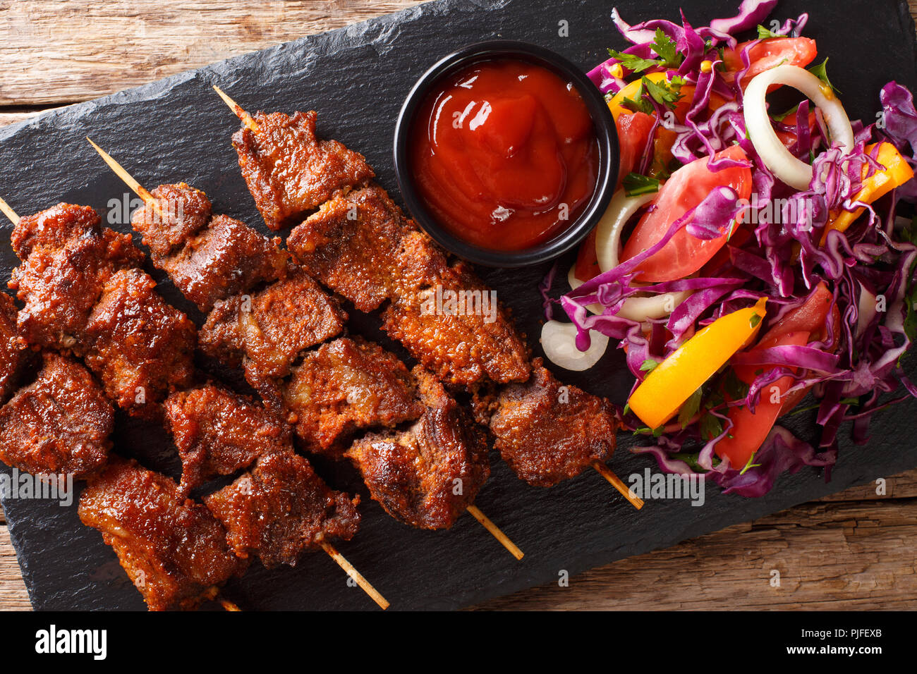 African food: spicy suya kebab on skewers with fresh vegetable salad ...